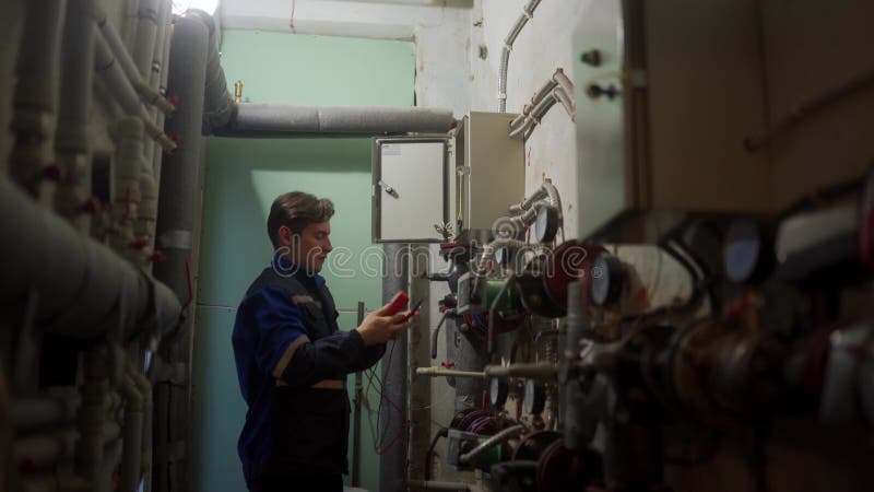 Electrician Inspecting Control Panel with Multimeter in a District ...