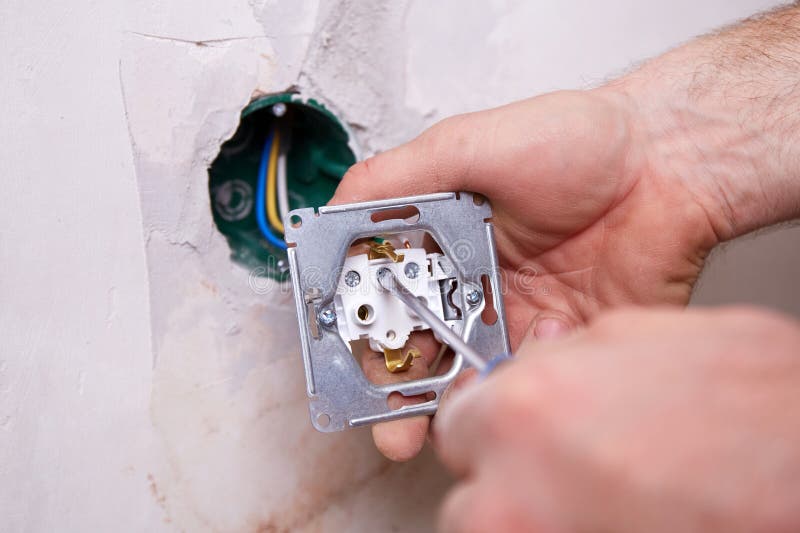 Electrician Installs an Electrical Outlet into a Wall Using a ...