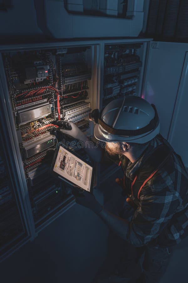 Electrician in Overalls, Focused on Work in Switchboard with Fuses ...