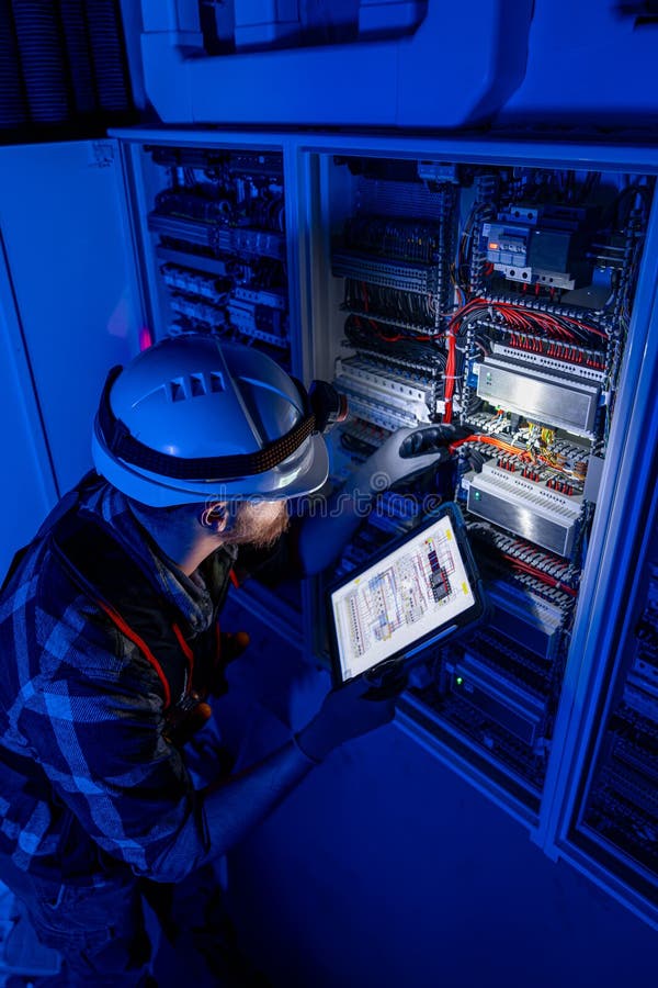 Electrician in Overalls, Focused on Work in Switchboard with Fuses ...