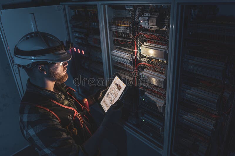 Electrician in Overalls, Focused on Work in Switchboard with Fuses ...