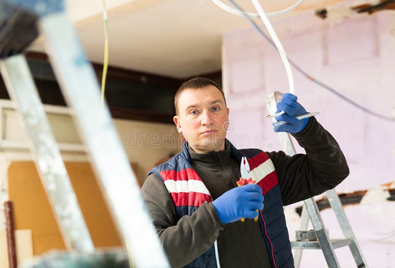 Electrician with Pliers in Hand Prepares Electrical Wiring in House ...