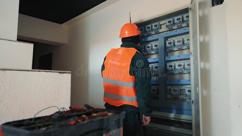 Electrician Working on a Panel, an Electrician in a Safety Vest and ...