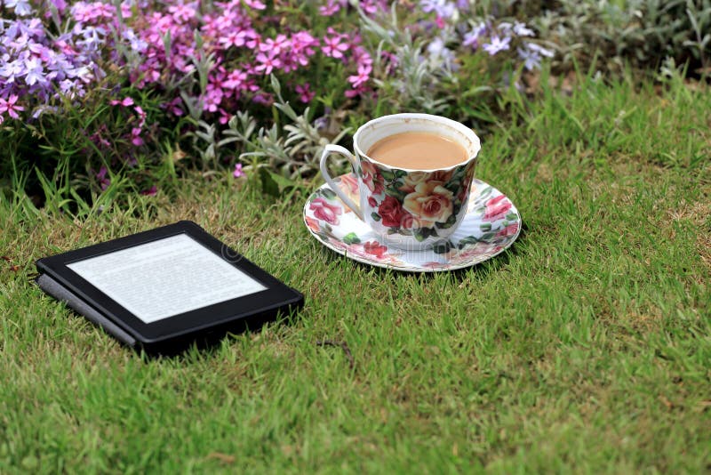 An Electronic Book Reader and a Cup of Coffee on the Grass Stock Photo ...