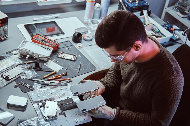 Technician Holds Two Identical Smartphones for Comparison, in One Hand ...
