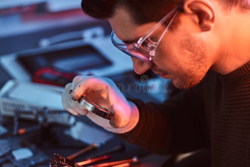 Electronic Technician Mending a Broken Tablet Carefully Examines the Chip of the Tablet Using a ...