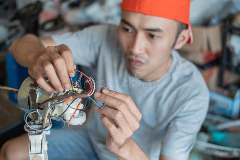 Electronics Repairman Smiles at the Camera while Holding the Fan Cable ...