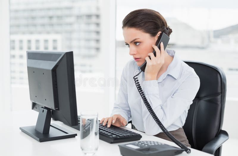 Elegant Businesswoman Using Landline Phone and Computer in Office Stock ...