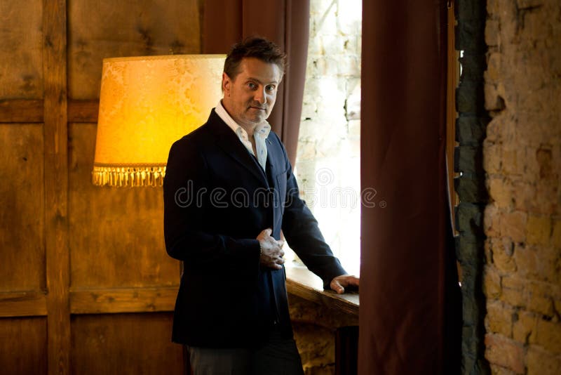 Elegant European Man Standing Near the Window and Touching His Jacket ... Elegant European Man Standing Near the Window and Touching His Jacket ...