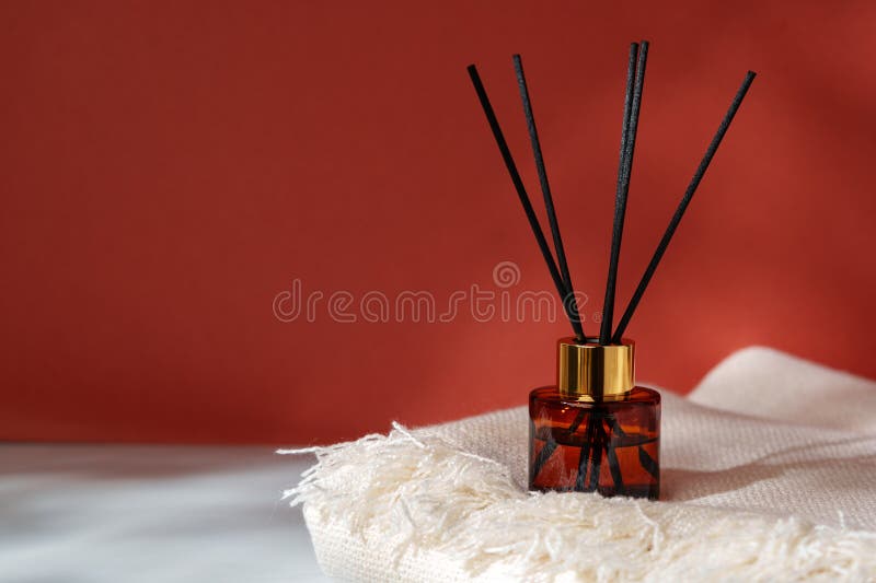 Elegant Reed Diffuser on White Textured Surface with Warm Red Backdrop ...