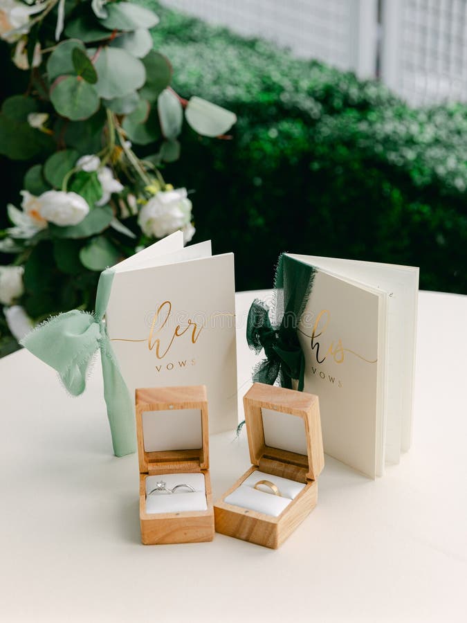 Elegant Wedding Vow Books and Rings Displayed on a Table with Greenery ...