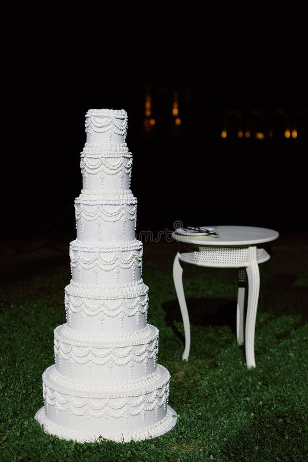 Elegant White Multi-tiered Wedding Cake on Grass Next To a Small Round Table at Night Stock ...
