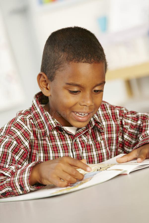 Elementary Age Schoolboy Reading Book in Class Stock Photo - Image of ...