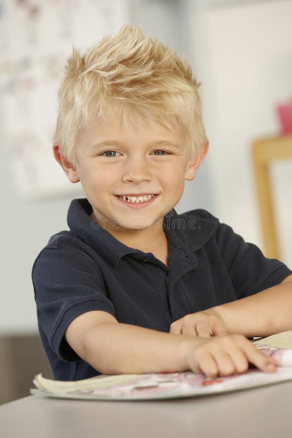 Elementary Age Schoolboy Reading Book in Class Stock Photo - Image of ...