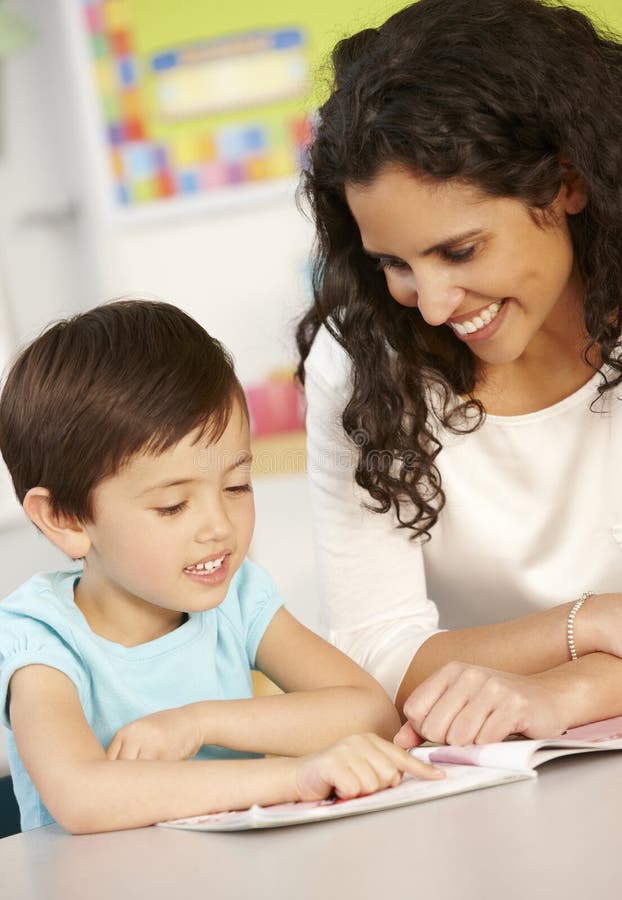 Elementary Age Schoolgirl Reading Book in Class with Teacher Stock ...