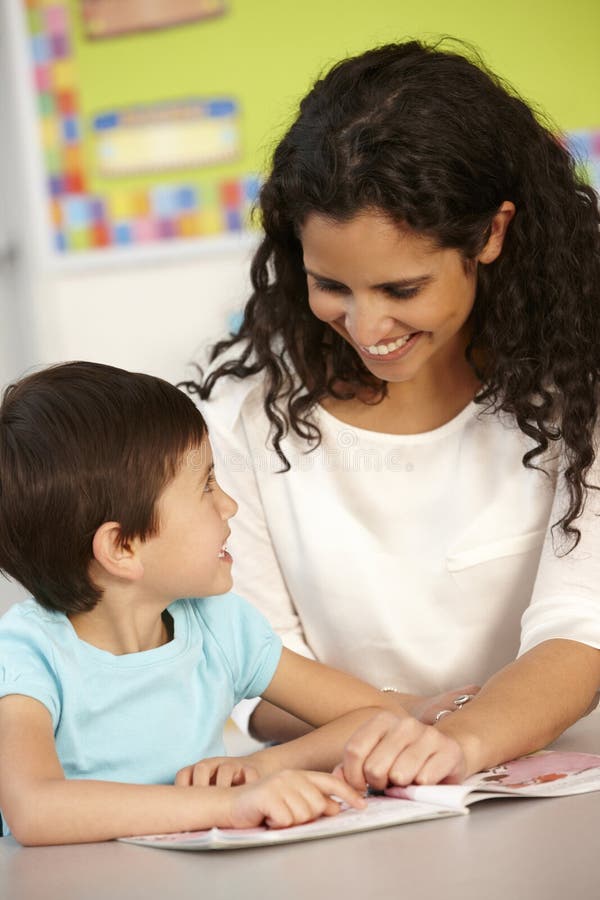 Elementary Age Schoolgirl Reading Book in Class with Teacher Stock ...
