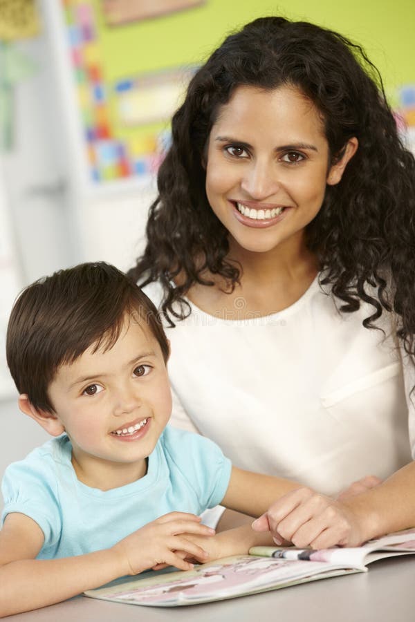 Elementary Age Schoolgirl Reading Book in Class with Teacher Stock ...