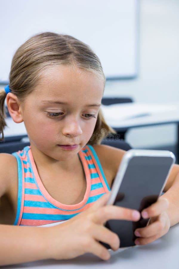 Elementary Girl Using Mobile Phone in Classroom Stock Photo - Image of ...