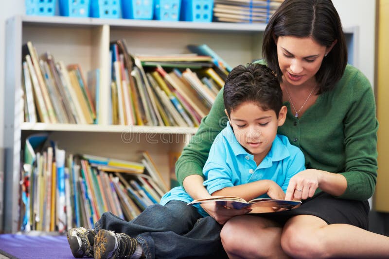 Elementary Pupil Reading with Teacher in Classroom Stock Image - Image ...