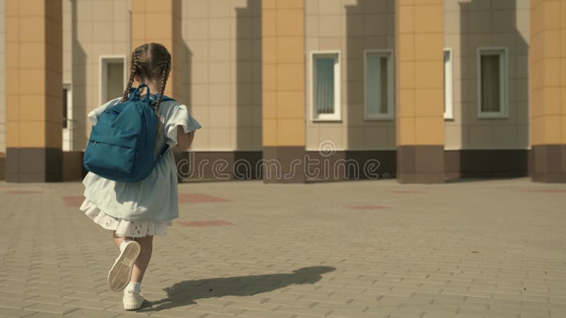 Elementary School Child is Running Around the School Yard with Backpack ...