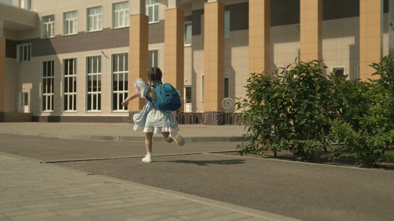 Elementary School Child is Running Around the School Yard with Backpack ...