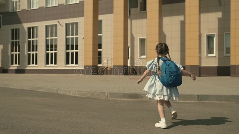 Elementary School Child is Running Around the School Yard with Backpack ...