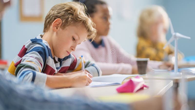 In Elementary School Classroom Brilliant Caucasian Boy Writes in ...