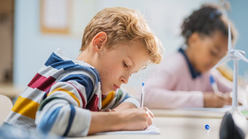 In Elementary School Classroom Brilliant Caucasian Boy Writes in ...