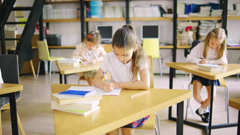 An Elementary School Girl is Doing Classwork in Her Notebook, and Her ...