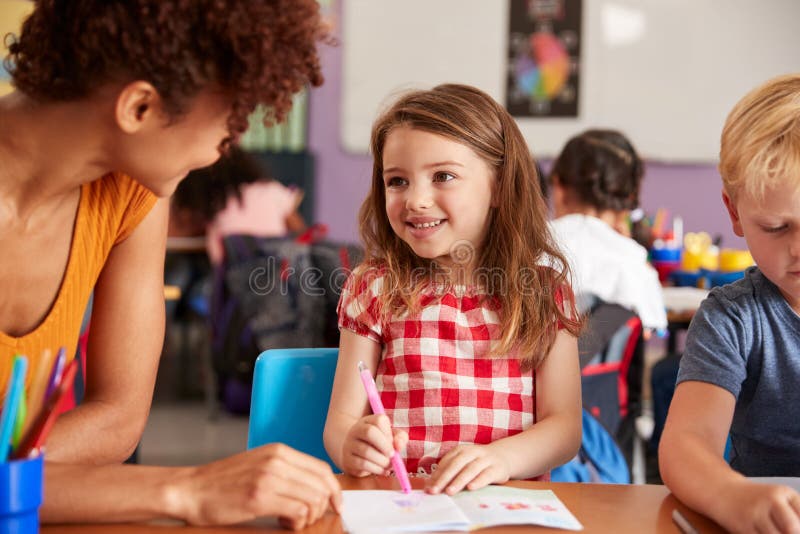 Elementary School Teacher Giving Female Pupil One To One Support in ...