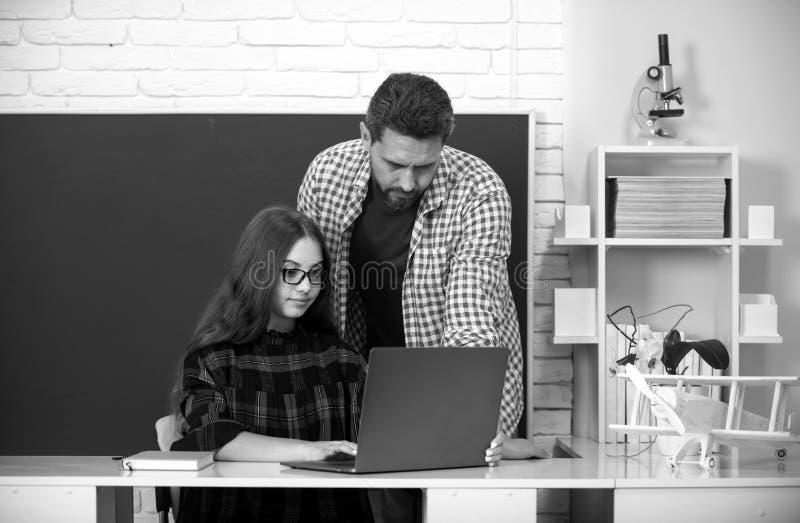 Elementary School Teacher and Pupil Doing Homework Using Computer ...