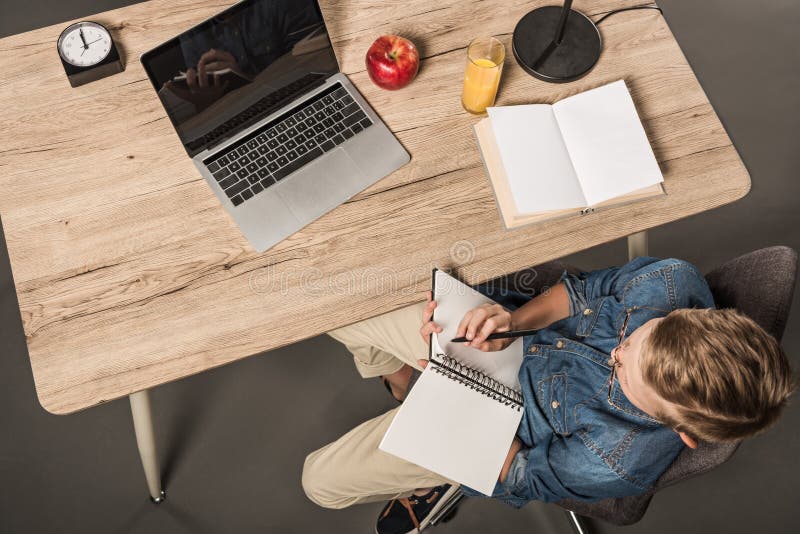Elevated View of Schoolboy Doing Homework with Textbook at Table with ...