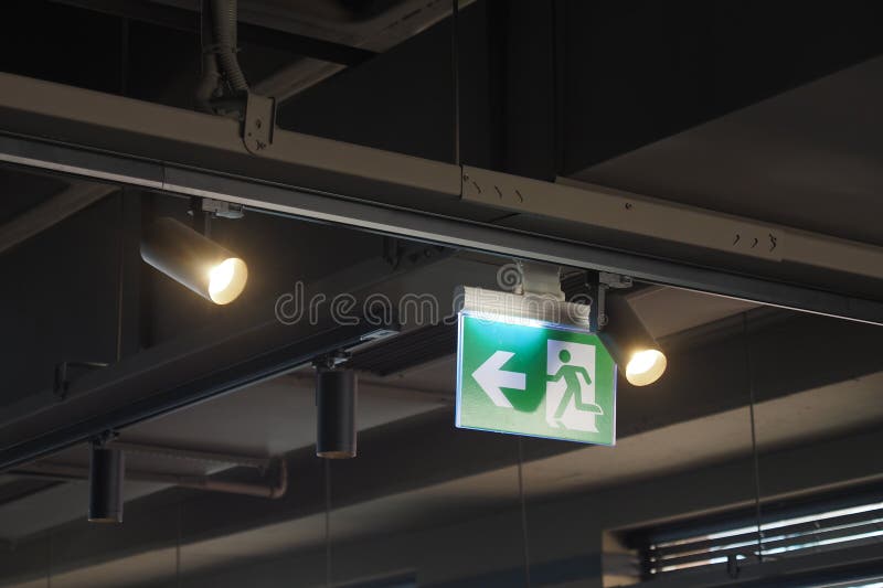 Emergency Exit Sign with Directional Arrow in a Dim Hallway Stock Image ...