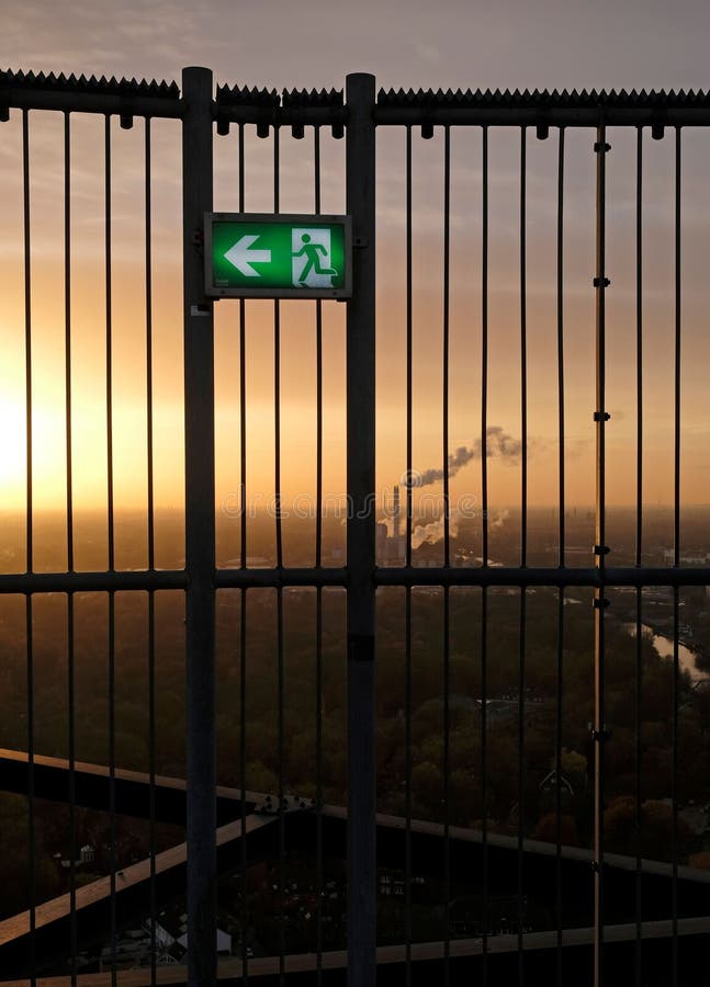 An Emergency Exit Sign with an Industrial Site in the Background Stock ...