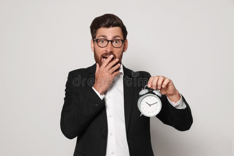 Emotional Bearded Man with Alarm Clock on Light Grey Background. Being ...
