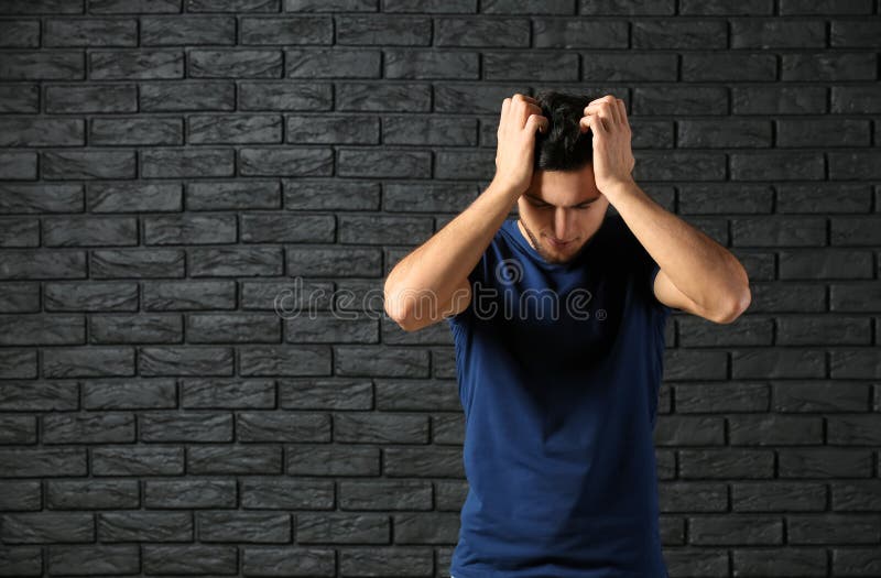 Emotional Young Man after Making Mistake Against Dark Brick Wall Stock ...