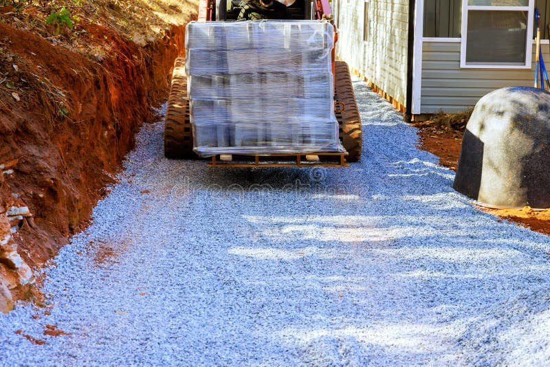 An Employee Unloading Using A Small Tractor Lifts Pallets Of Concrete Blocks For Retaining Wall