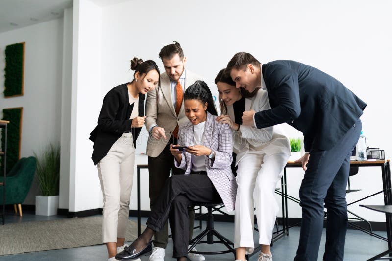 Employees in the Office Stand Around a Woman Playing on a Smartphone ...