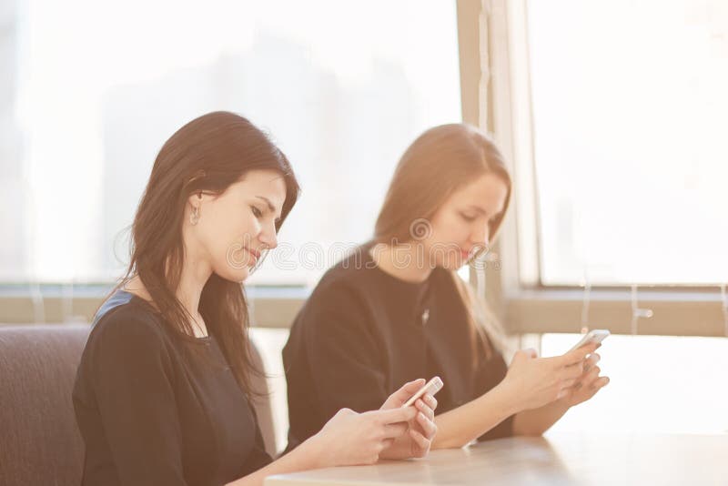 Employees Using Their Smartphones Sitting at a Table in a Cafe Stock ...