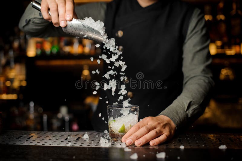 Empregado De Bar Que Adiciona Cubos De Gelo No Vidro De Cocktail ... Empregado De Bar Que Adiciona Cubos De Gelo No Vidro De Cocktail ...