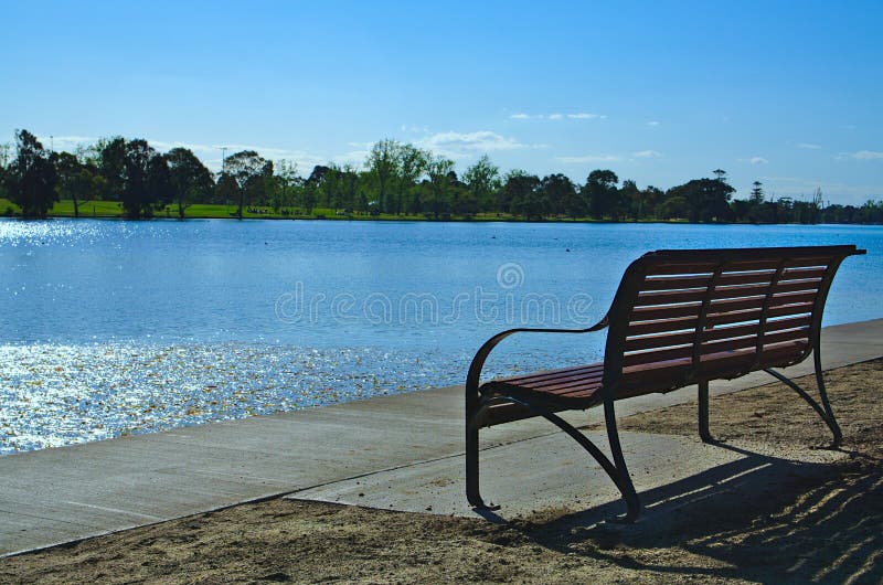 Empty Bench Facing Lake with Blue Sky and Blue Water Stock Image ...