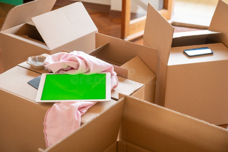 Empty Cardboard Boxes Ready To Be Open Along with a Tablet with Green ...