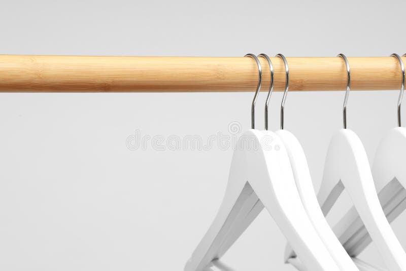 Empty Clothes Hangers on Wooden Rail Against Light Background, Closeup ...
