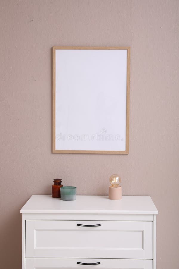 Empty Frame Hanging on Pale Rose Wall Over Chest of Drawers in Room ...