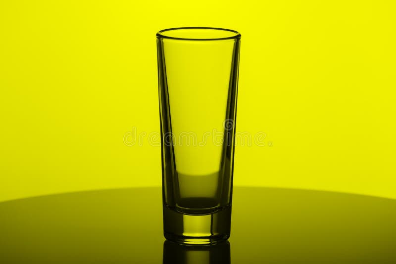 Empty Glass for Vodka on a Reflective Surface on a Yellow Background ...