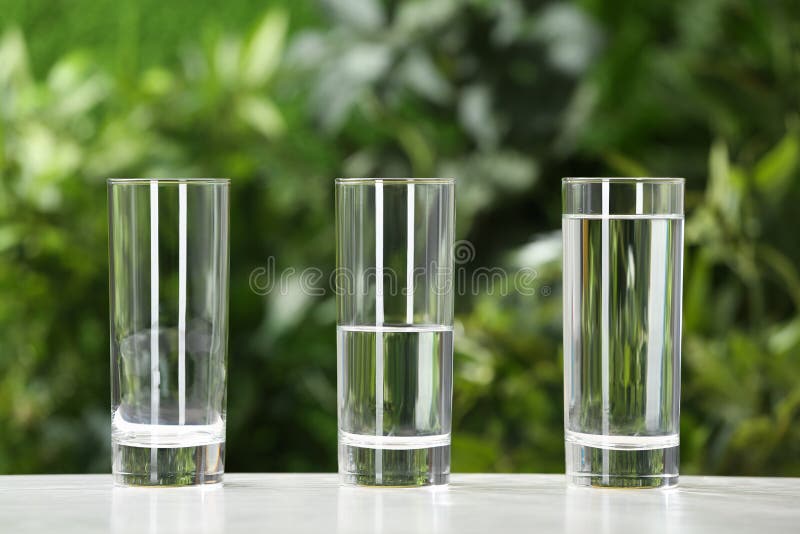 Empty, Half and Full Glasses of Water on White Table Stock Photo ...