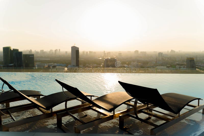Empty Lounge Chairs beside a Rooftop Infinity Pool at Sunset with ...