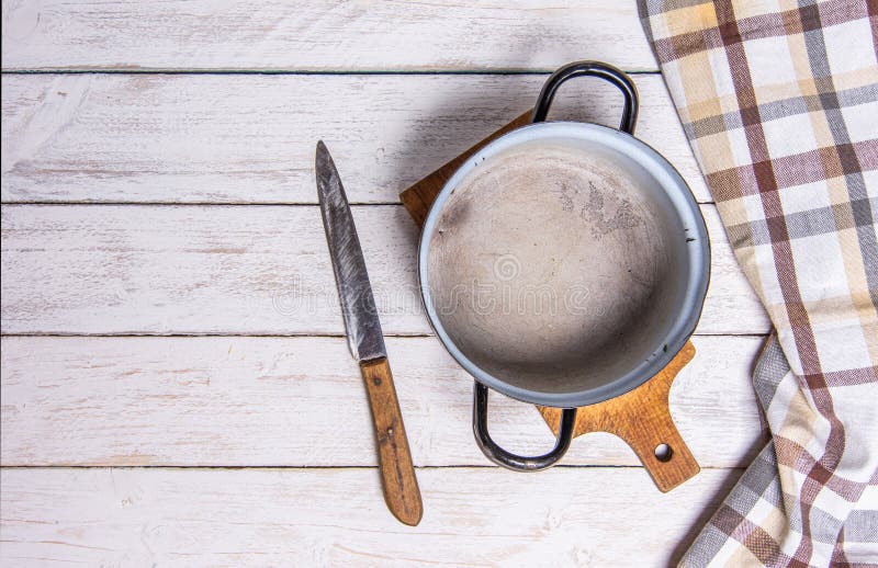 Empty Old Enamel Pot and Rustic Knife on White Boards. Checkered Table ...
