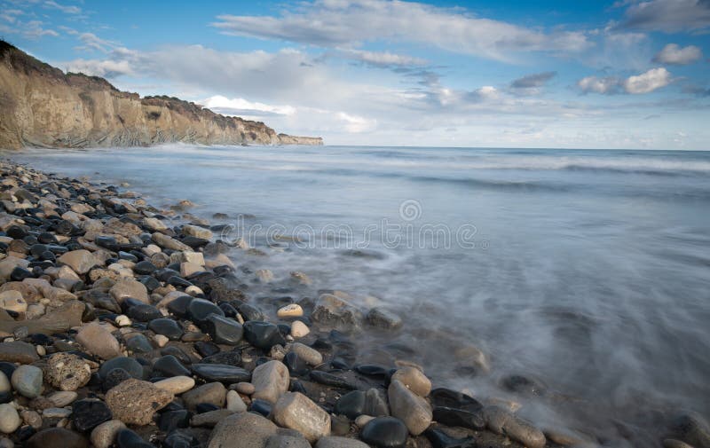 Empty Pebble Tropical Beach Under Cliffs with Windwaves and Cloudy Sky ...