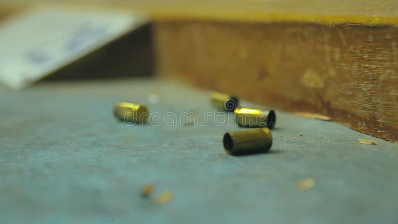 Empty Pistol Bullet Shells Dropping and Impacting Wooden Table in a ...